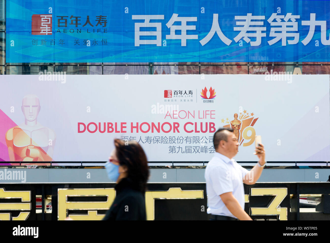 --FILE--Pedestrians walk past an advertisement of Chinese Aeon Life ...