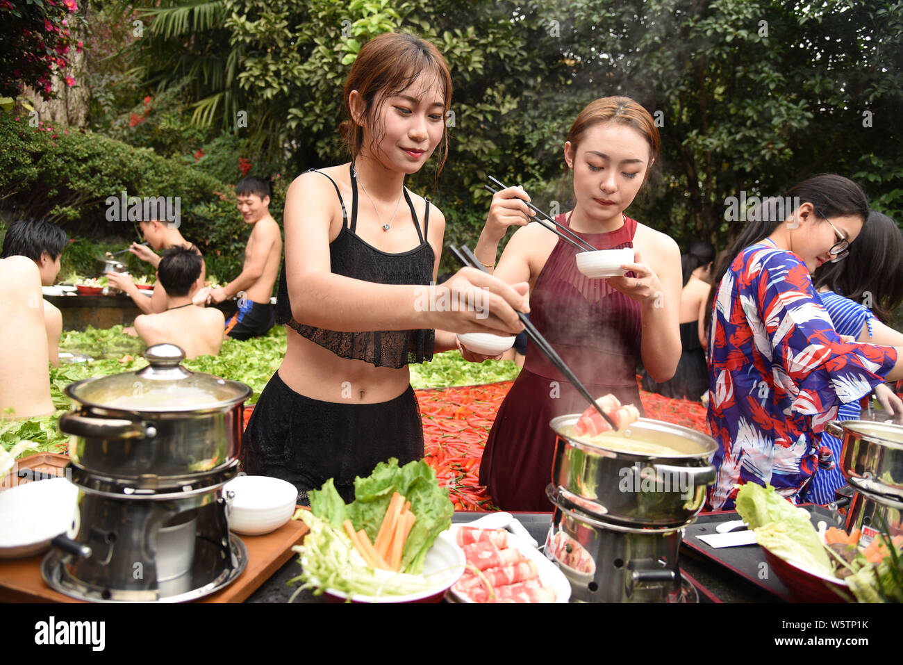 Visitors enjoy hot pots while soaking in a "Yuan Yang" hotpot-style hot ...