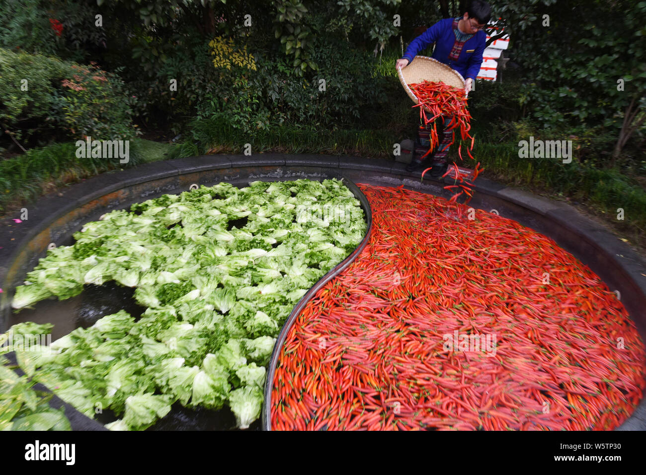 Workers prepare a hotpot-style hot spring half filled with peppers and ...
