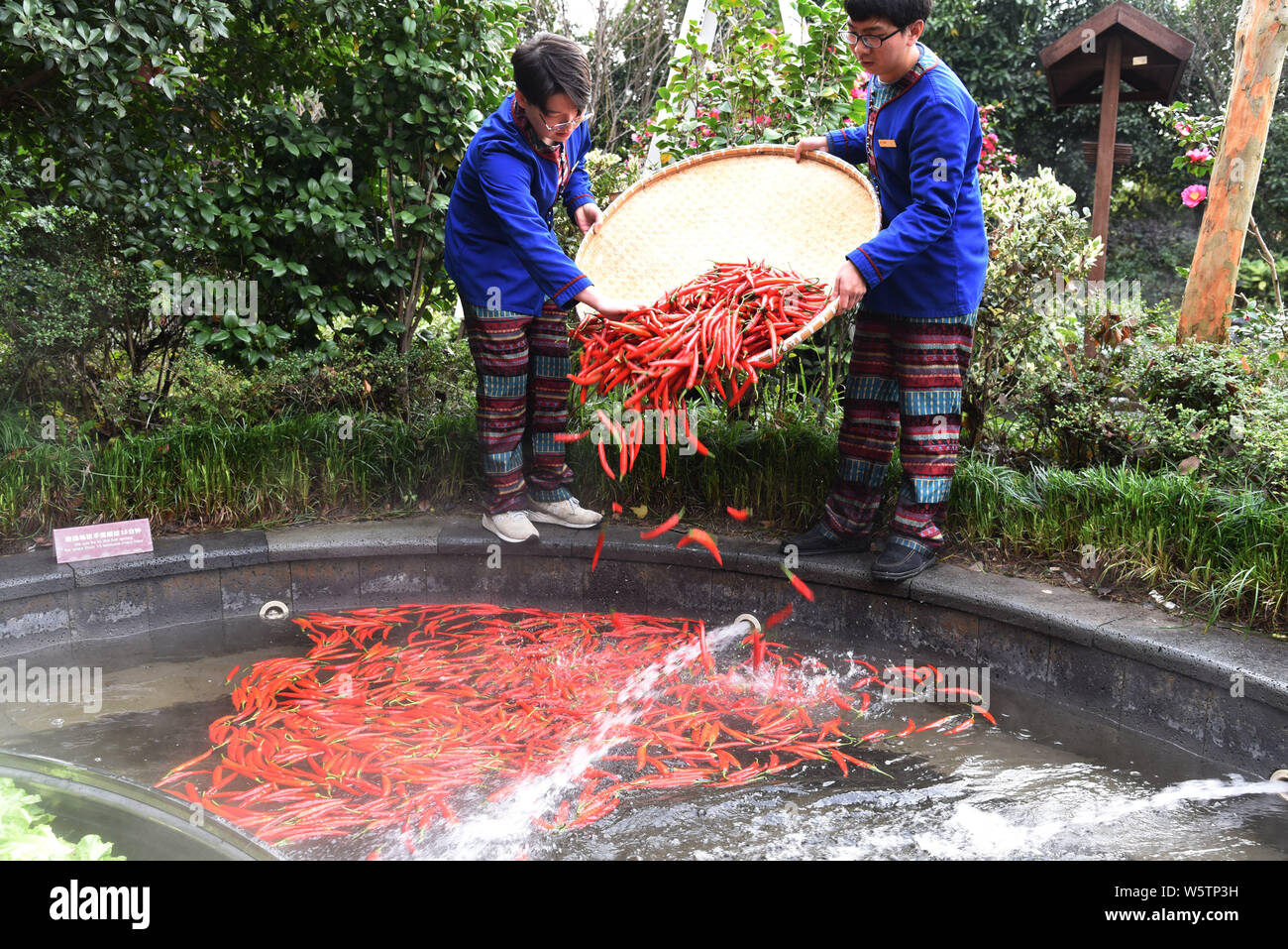 Workers prepare a hotpot-style hot spring half filled with peppers and ...