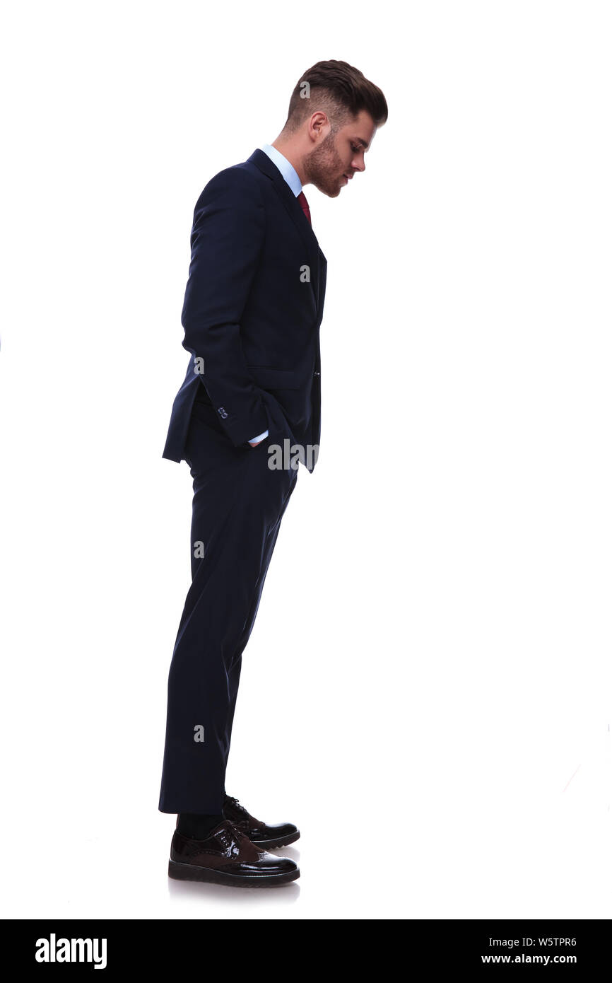 young businessman waiting in line looks down at something while ...