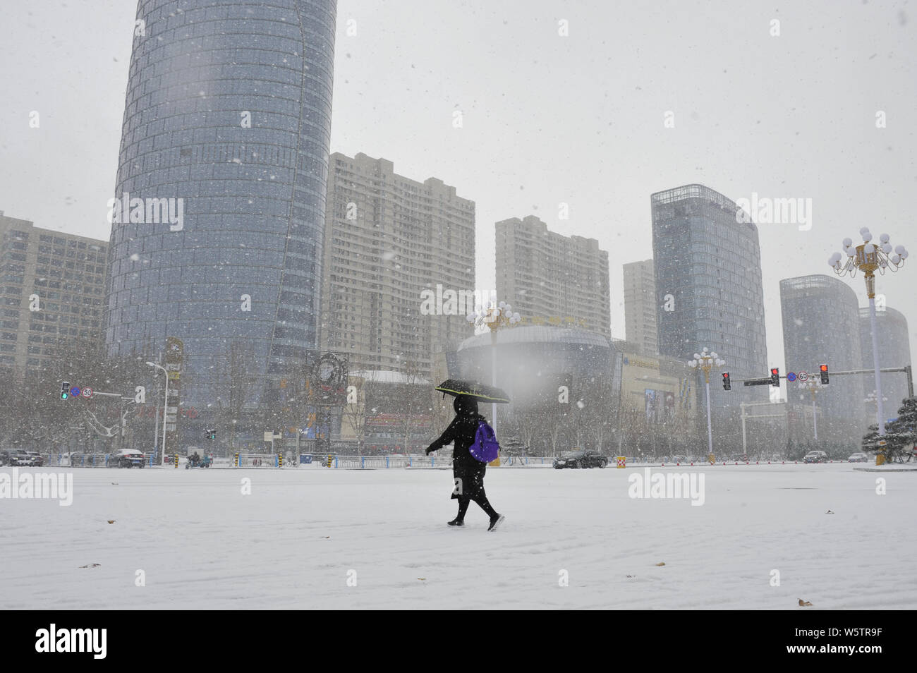 A local resident walks on a snow-covered road during a heavy snowfall ...