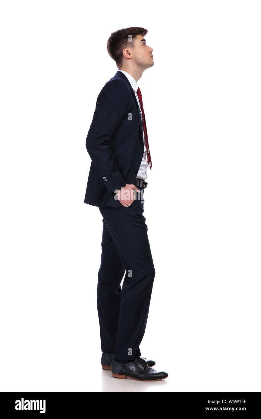 Side view of businessman wearing a navy suit and a red tie waiting in ...