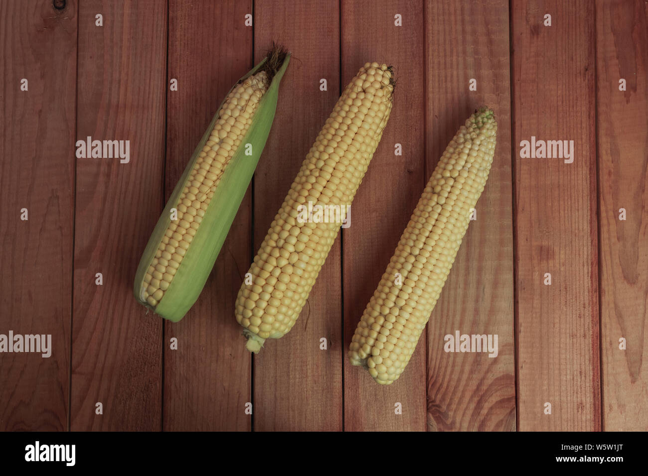 Fresh Sweet corn on a red wooden table background Stock Photo - Alamy