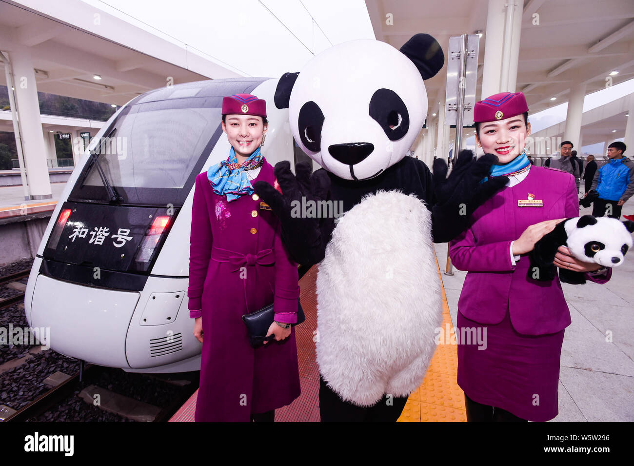 Chinese train attendants pose with a worker dressed in giant panda ...