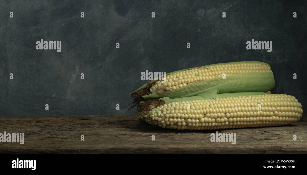 Fresh Sweet corn on a old oak wooden table and beautiful grey wall ...