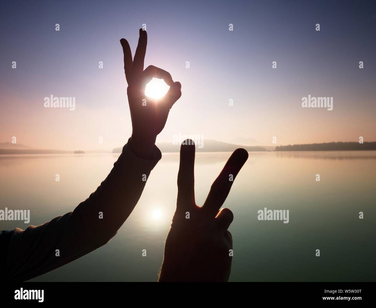 Fingers gesturing picture frame on sunrise seaside. Sunlight on beach ...