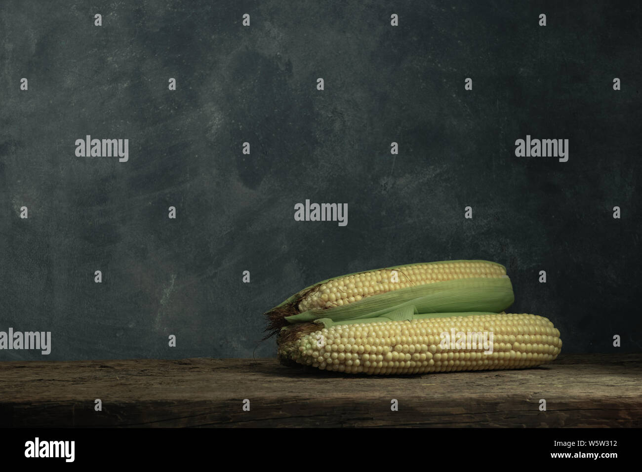 Fresh Sweet corn on a old oak wooden table and beautiful grey wall ...