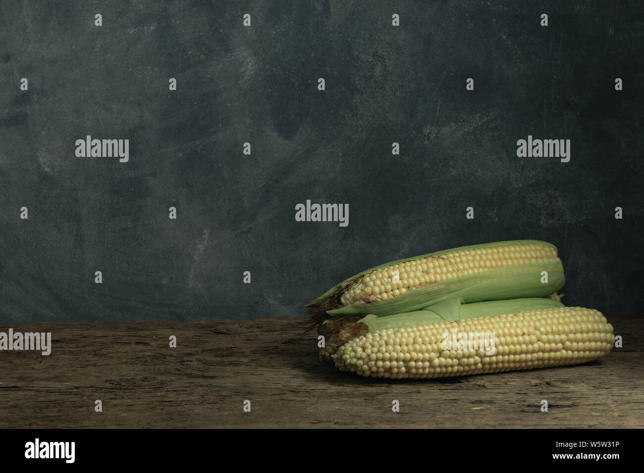 Fresh Sweet corn on a old oak wooden table and beautiful grey wall ...