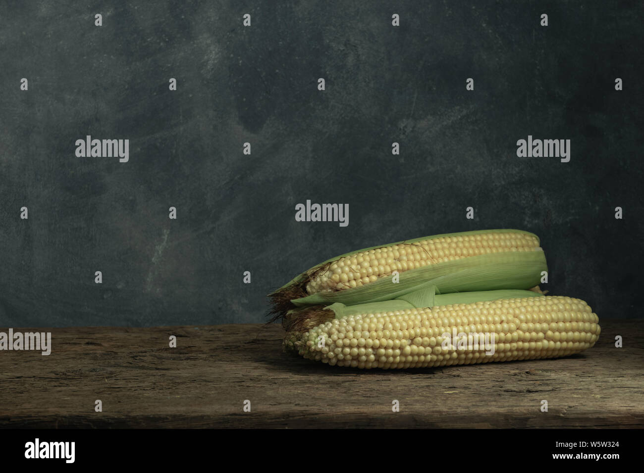 Fresh Sweet corn on a old oak wooden table and beautiful grey wall ...