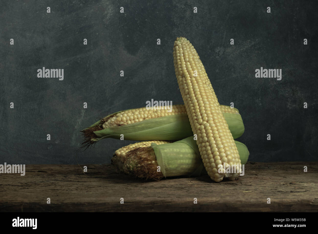 Fresh Sweet corn on a old oak wooden table and beautiful grey wall ...