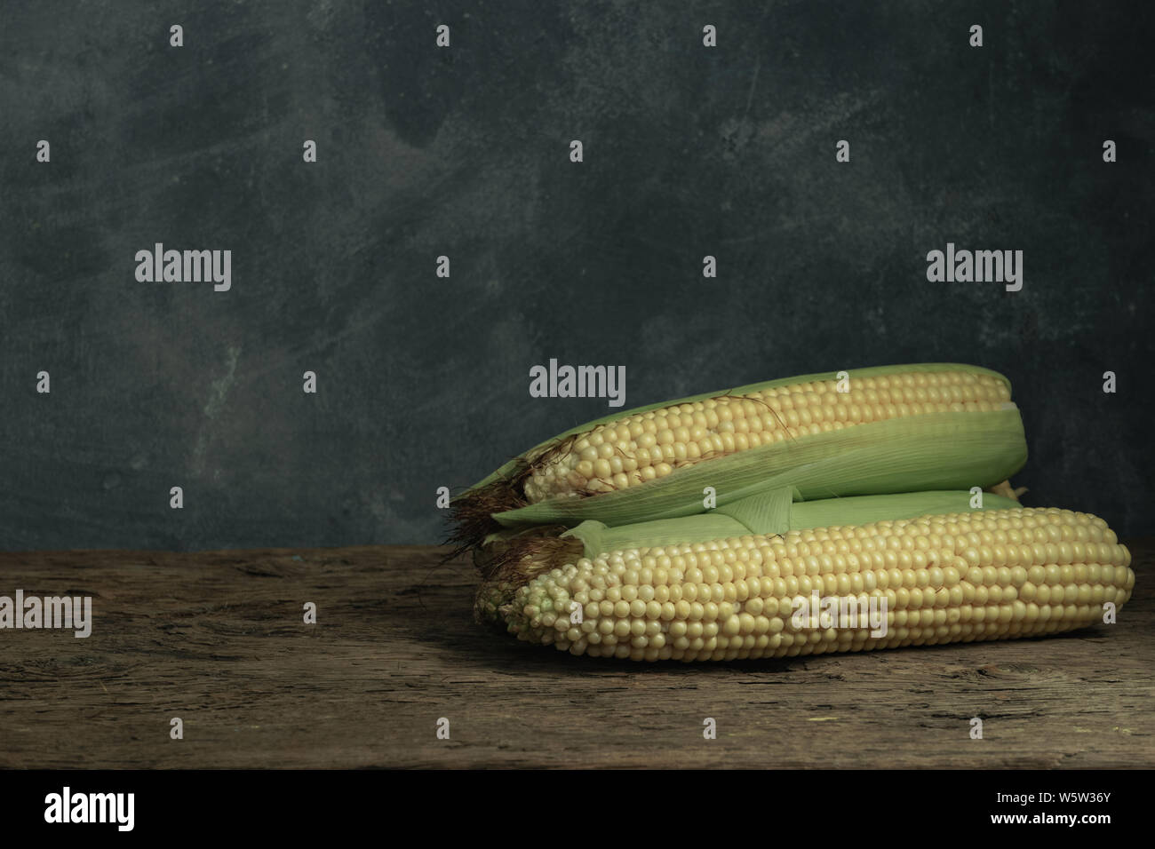 Fresh Sweet corn on a old oak wooden table and beautiful grey wall ...