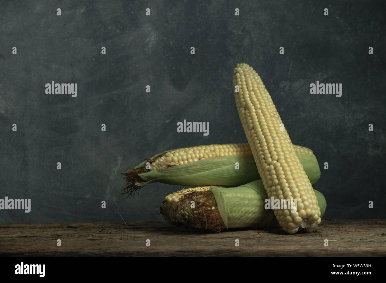 Fresh Sweet corn on a old oak wooden table and beautiful grey wall ...