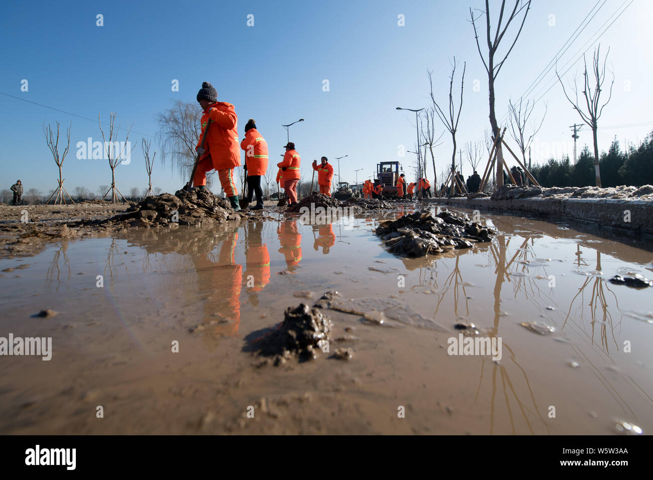 Chinese sanitation workers clear away mud and stone after a leakage of ...