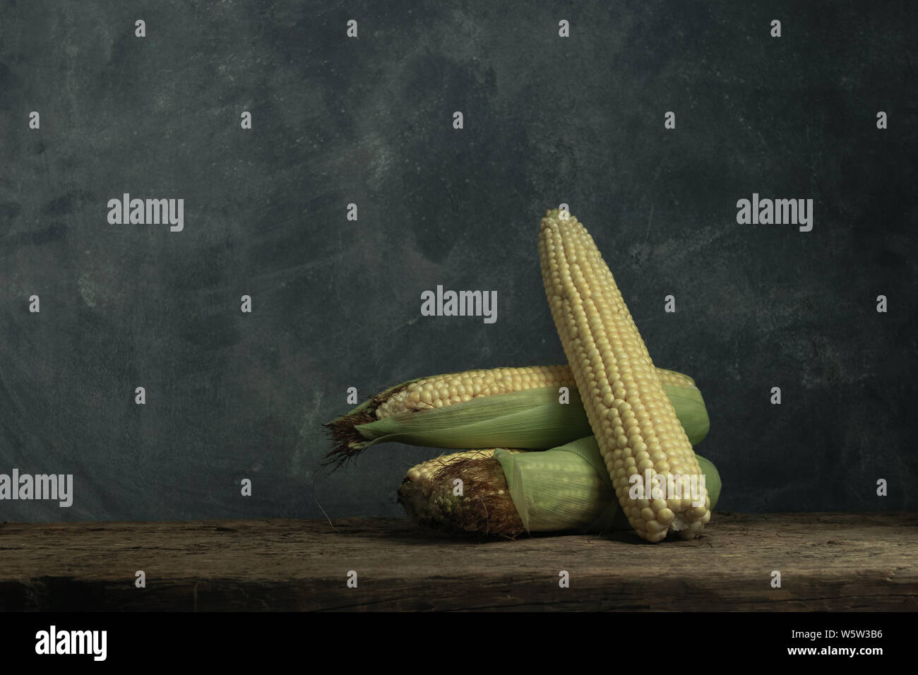 Fresh Sweet corn on a old oak wooden table and beautiful grey wall ...