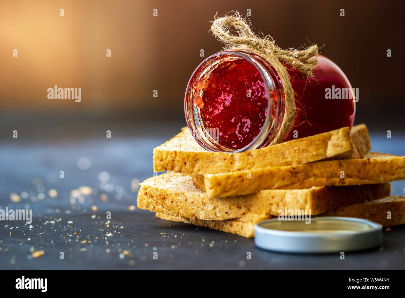 Strawberry jam bottle and whole wheat bread are stacked on a black ...