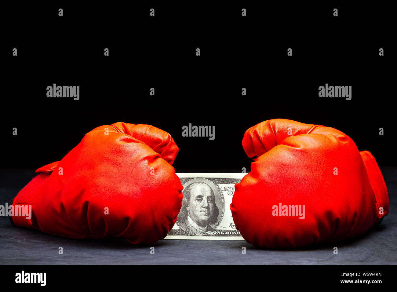 Red boxing gloves holding the dollar banknote on cement floor in ...