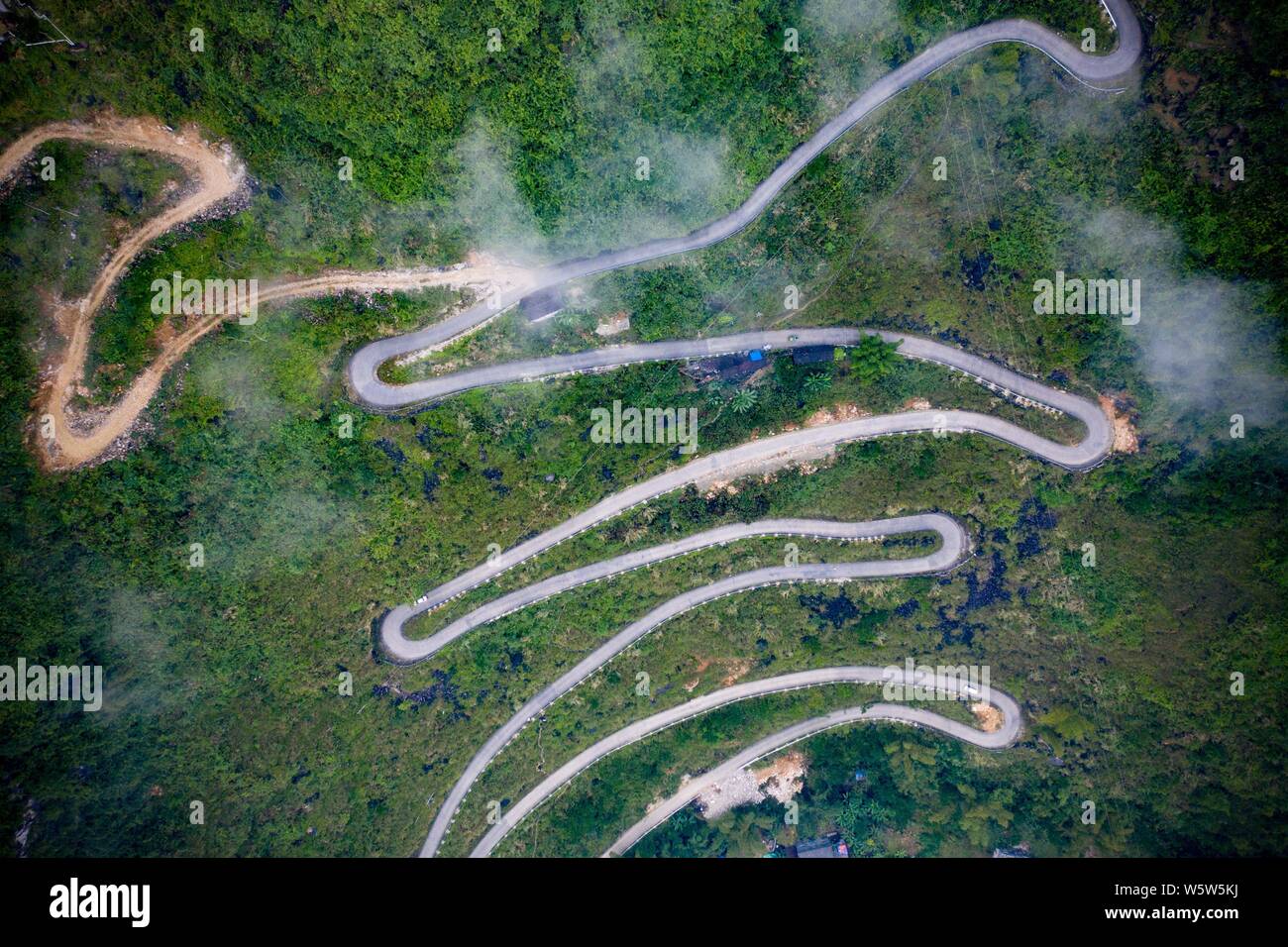 Aerial view of a winding mountain road around mountains in Du'an Yao ...
