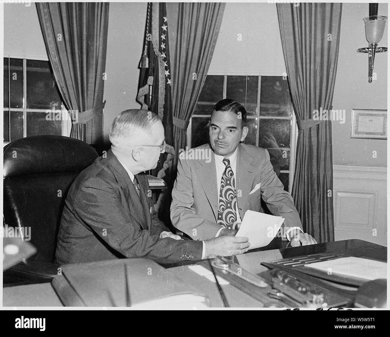 Photograph of President Truman in the Oval Office conferring with ...
