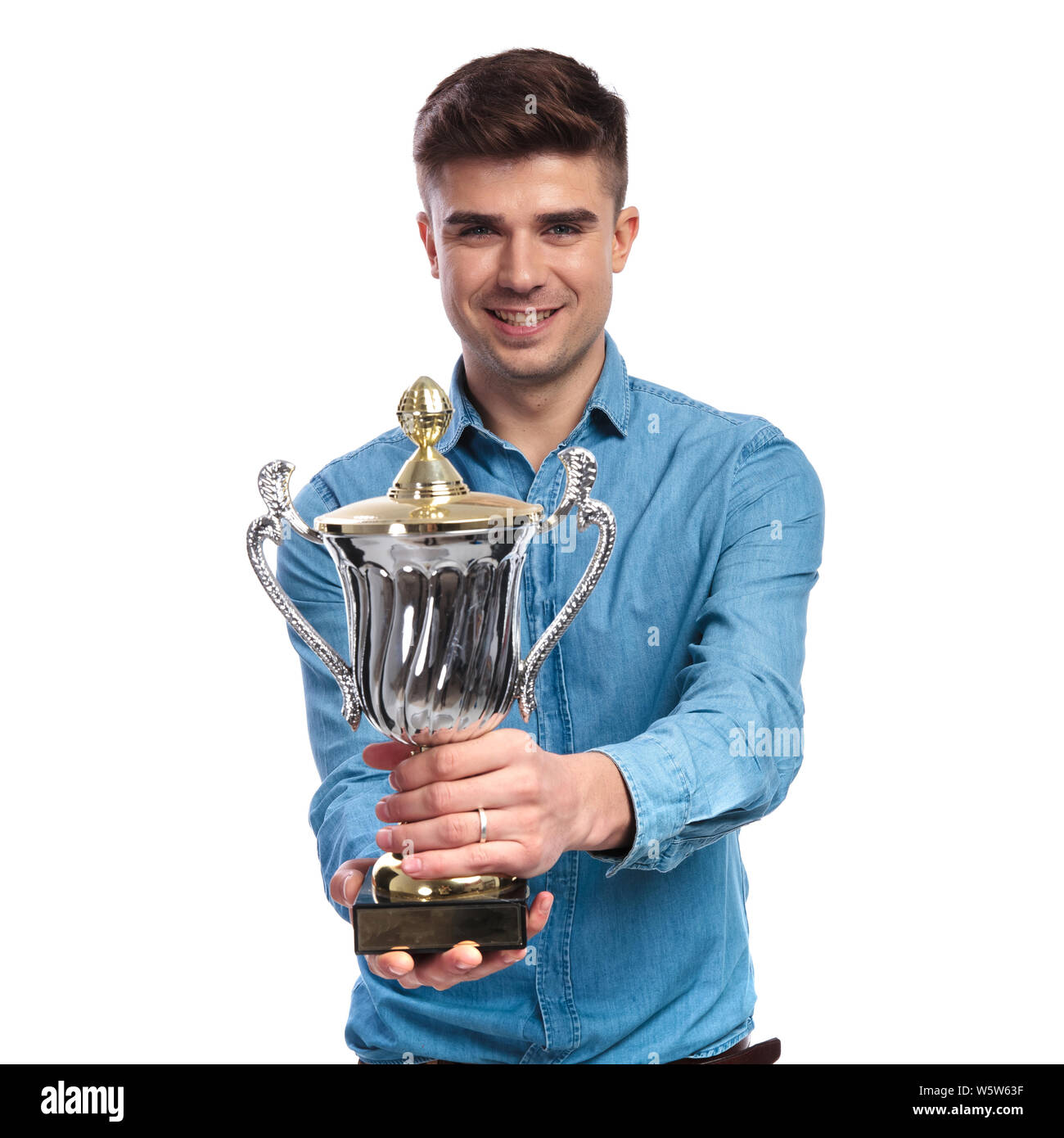 young smiling casual man offering his trophy cup award to you on white ...