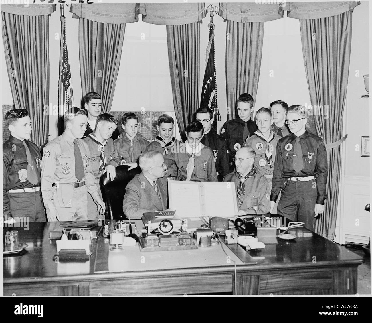 Photograph of President Truman in the Oval Office, receiving a report ...