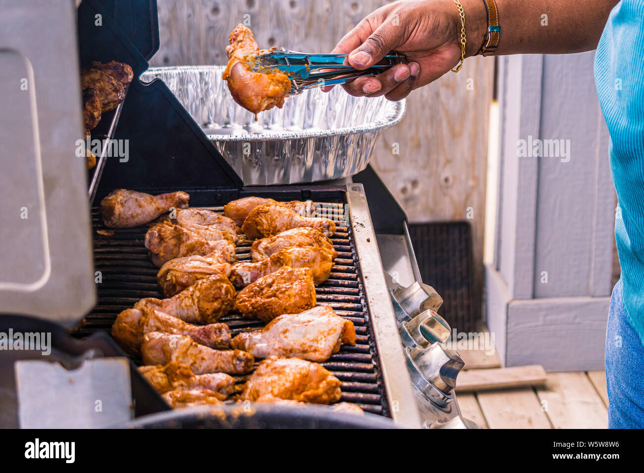 African American Nigerian man grilling roasting chicken thighs on ...