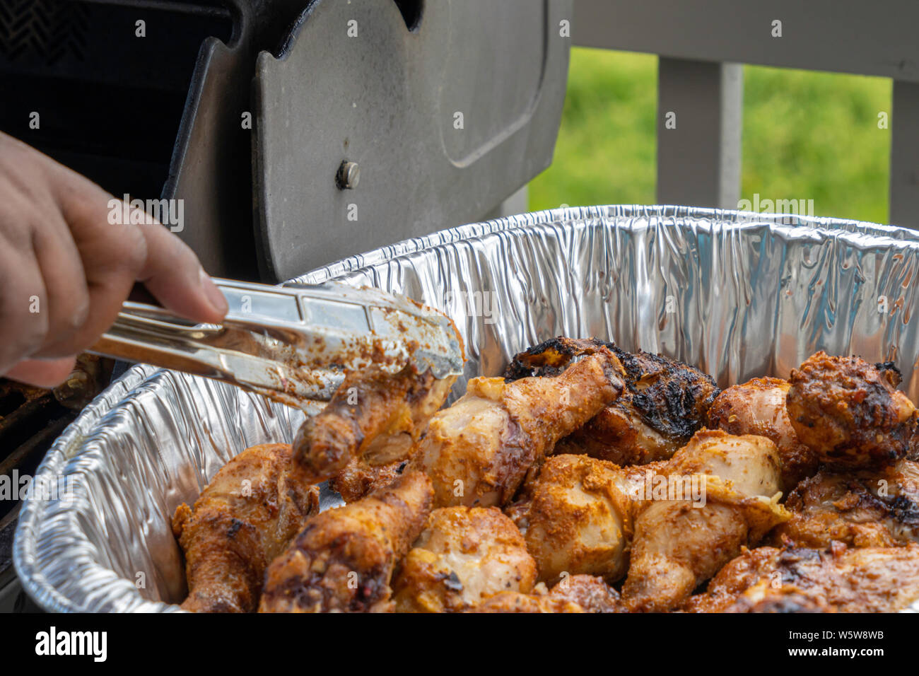 African American Nigerian man grilling roasting chicken thighs on ...