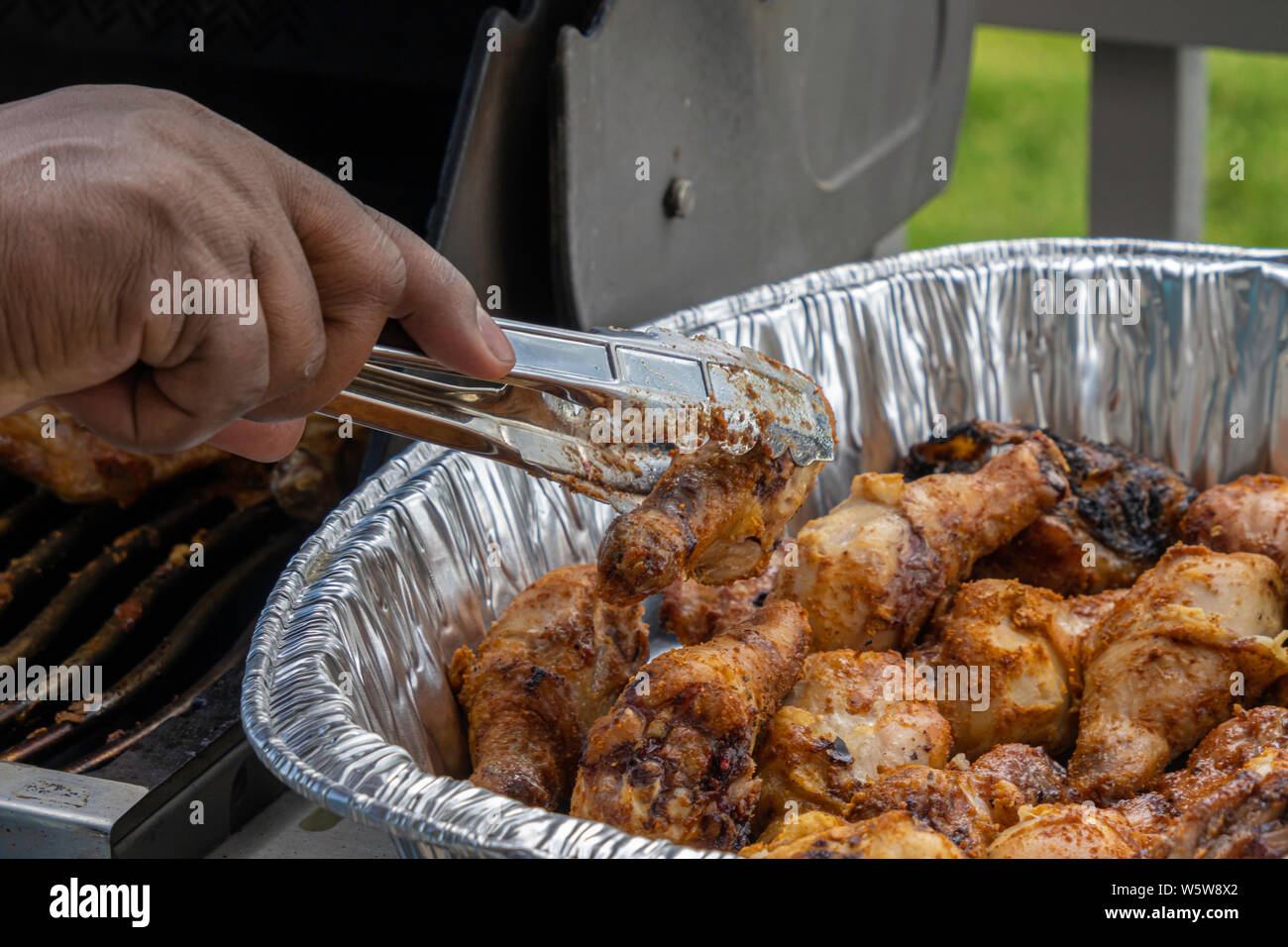 African American Nigerian man grilling roasting chicken thighs on ...