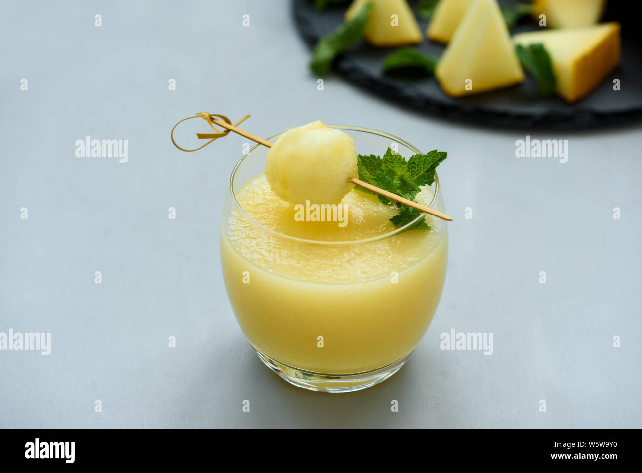Cold fresh melon smoothie with melon ball and mint leaves on gray ...