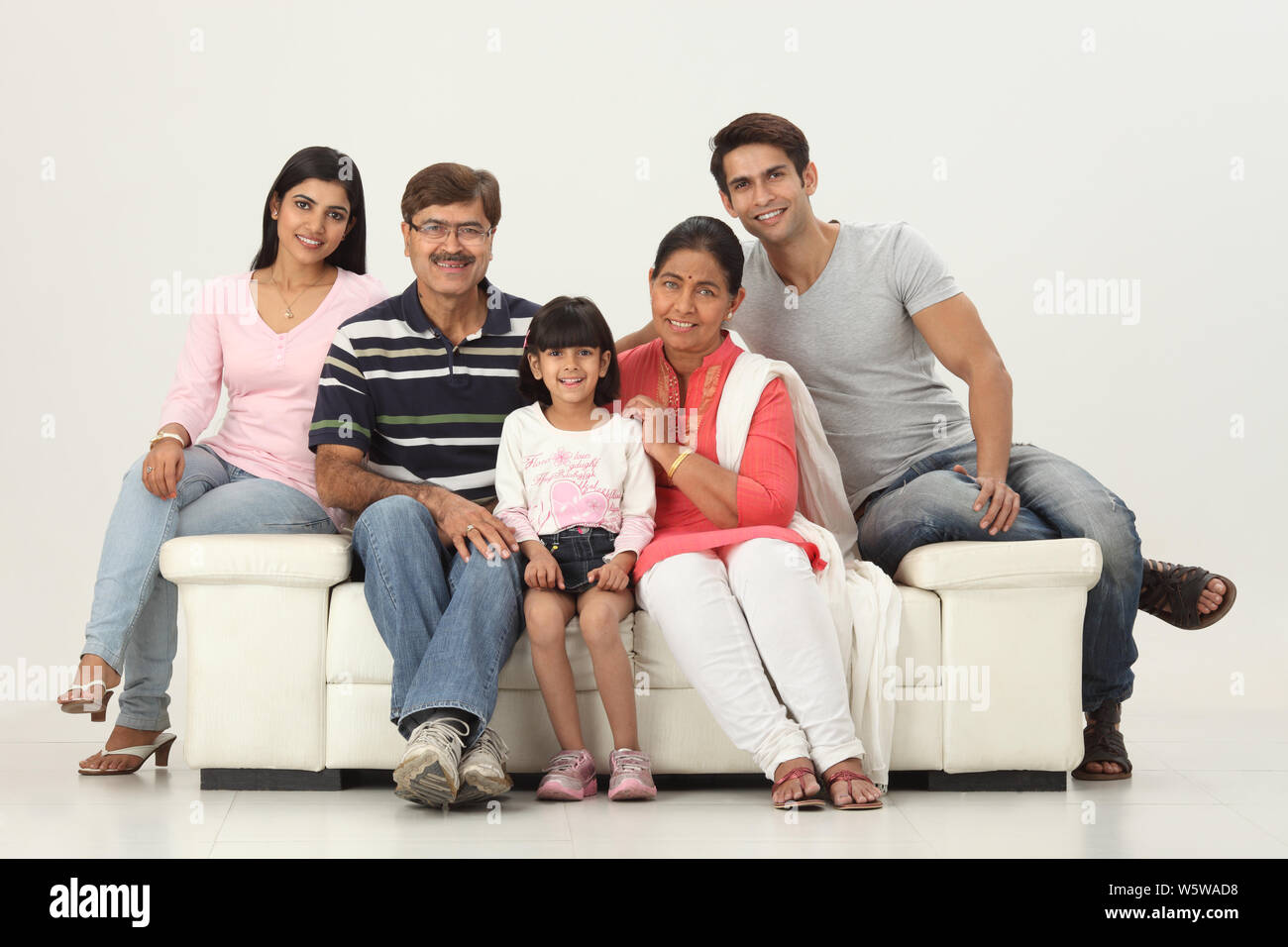 Family sitting on a couch and smiling Stock Photo - Alamy