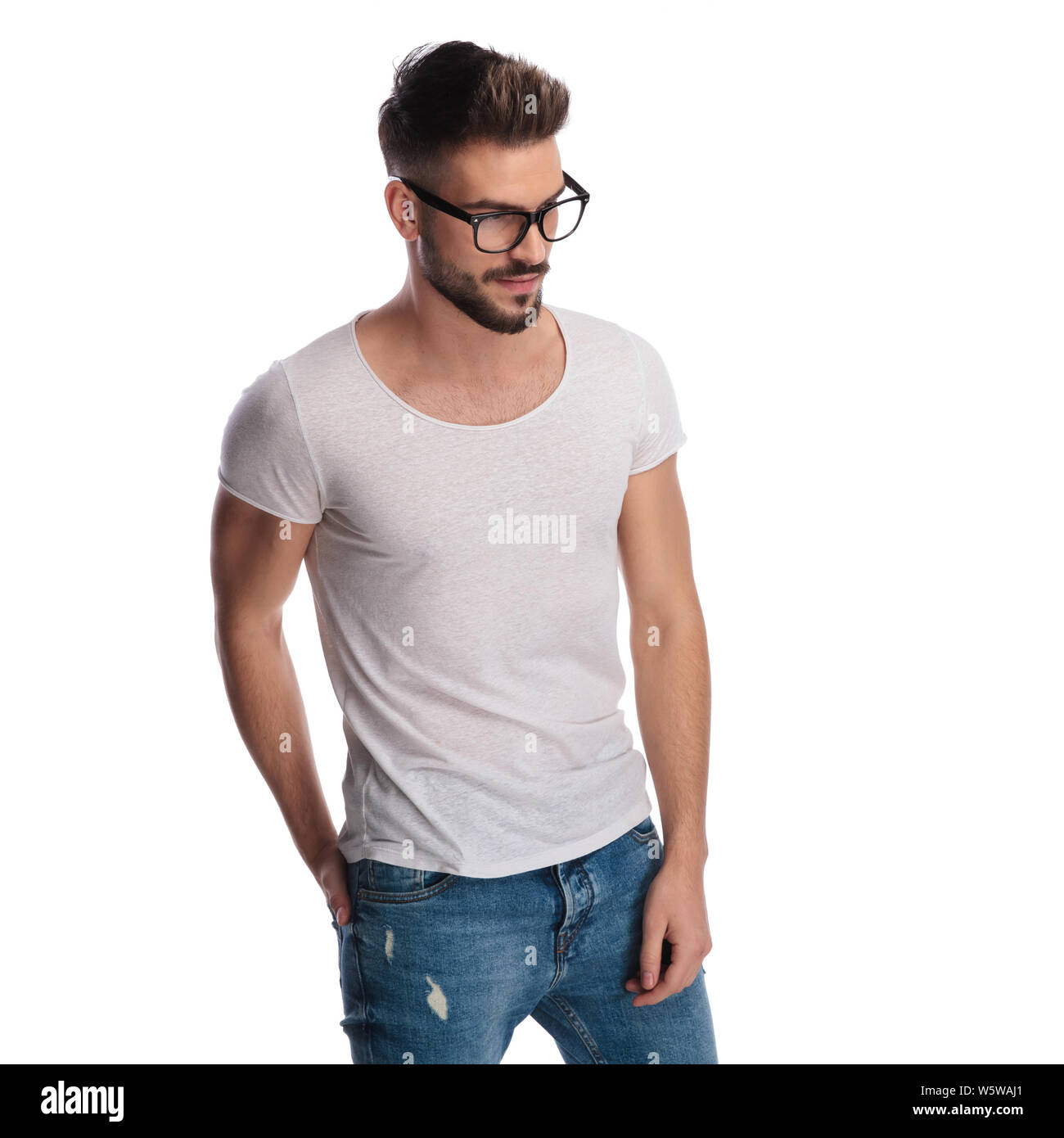 side view of a casual young man with hand in back pocket standing on ...