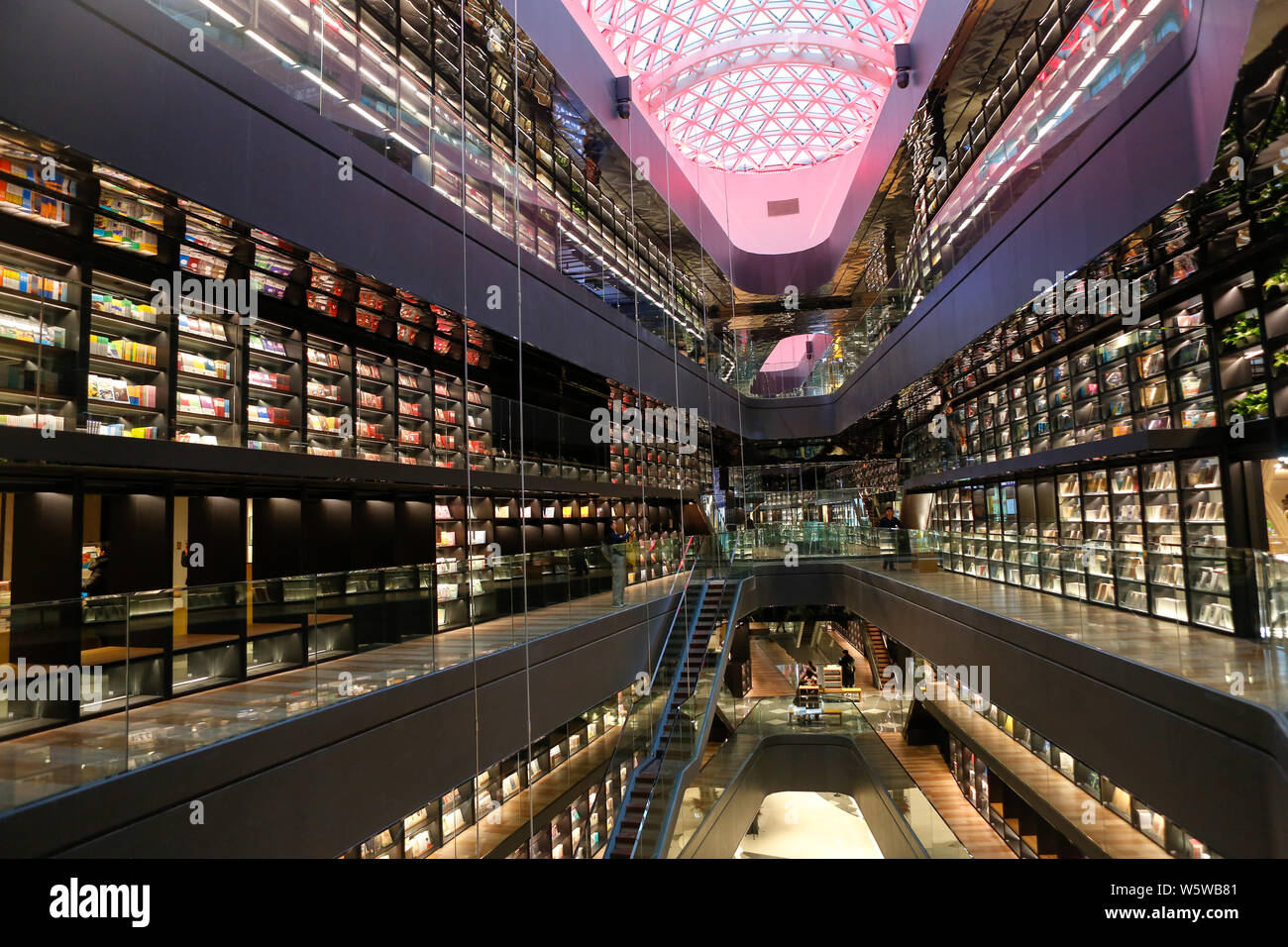 Books are placed on the four-storey-high book wall decorated with glass ...