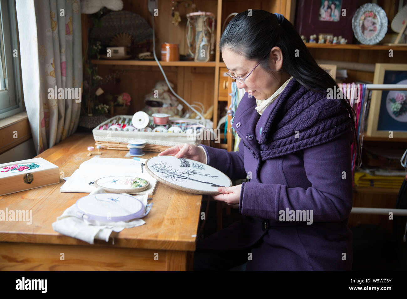 Chinese craftswoman Yuan Weilin makes an embroidery through silk ribbon ...