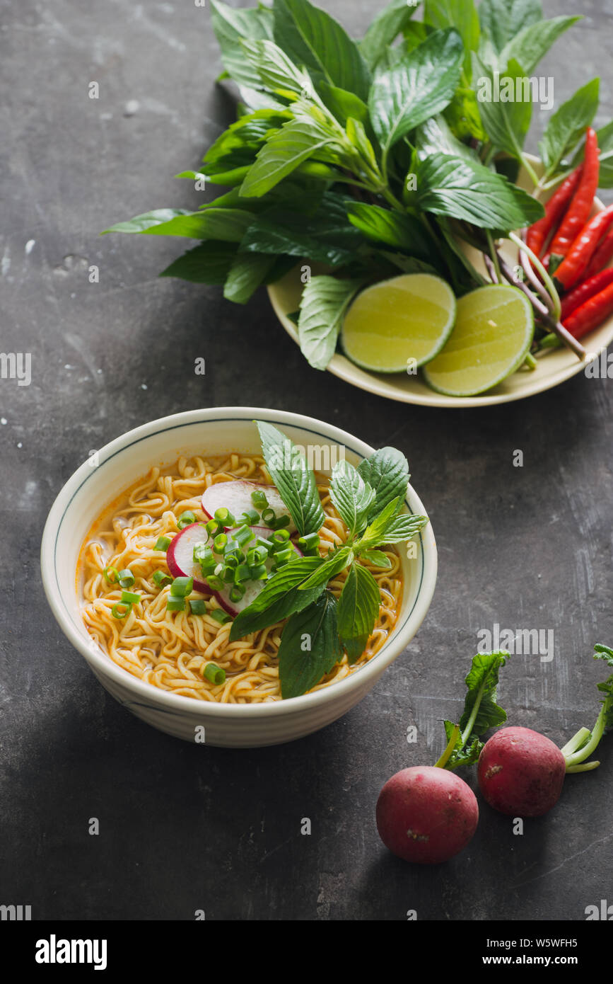 Instant noodles in bowl with fresh herbs, garnish of cilantro and Asian ...