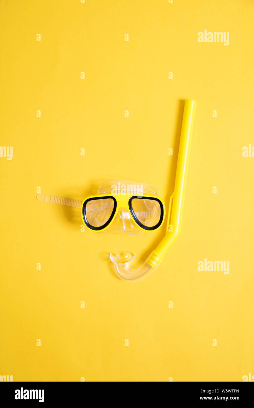 A yellow snorkel and diving mask on a yellow background. overhead lay ...