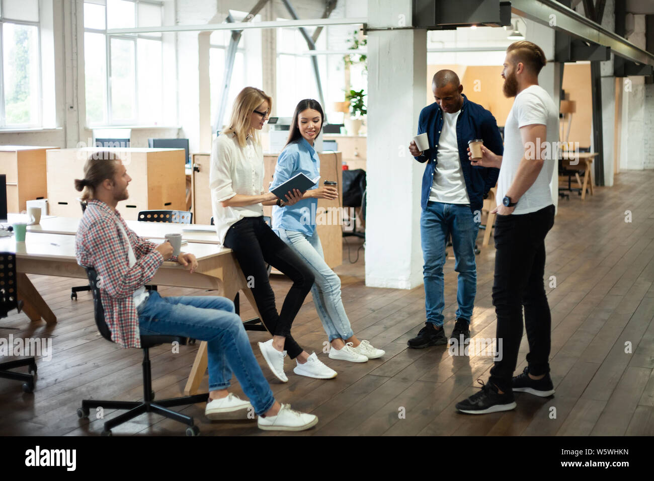 Young modern colleagues in smart casual wear working together while ...