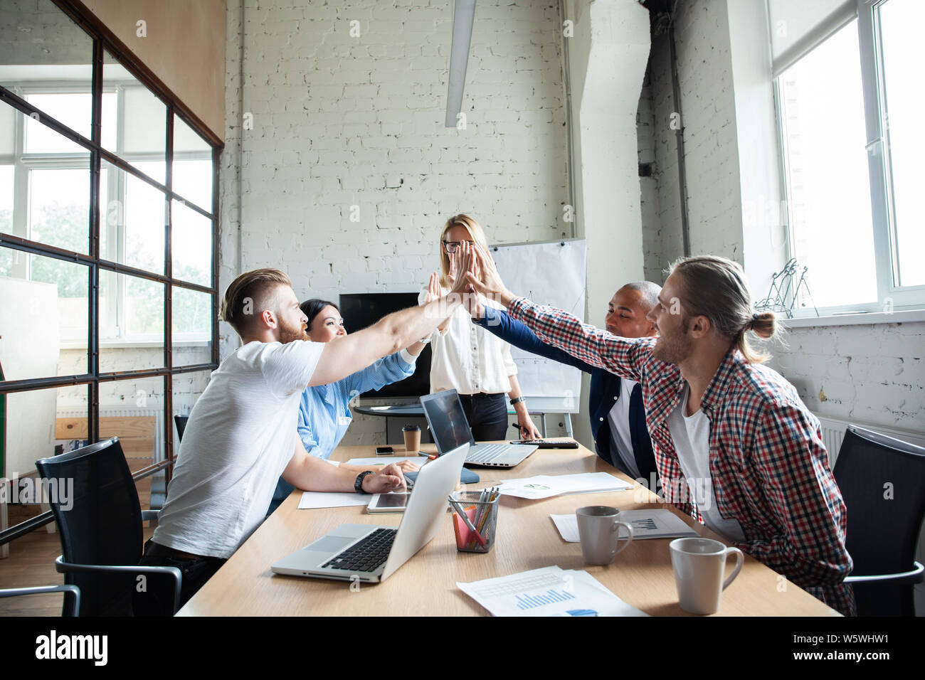 Happy successful multiracial business team giving a high fives gesture ...