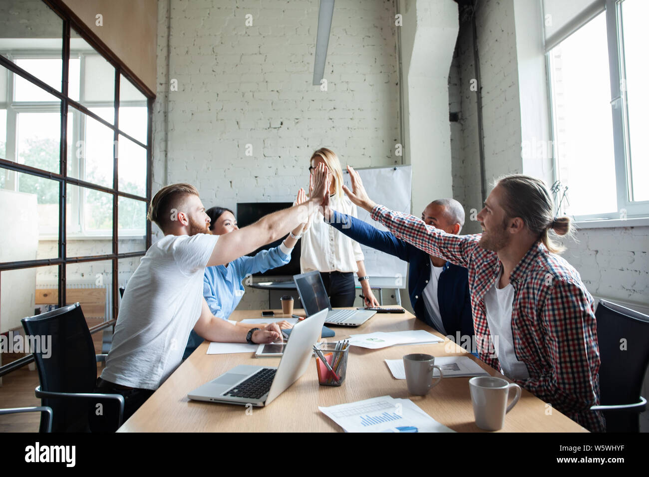 Happy successful multiracial business team giving a high fives gesture ...