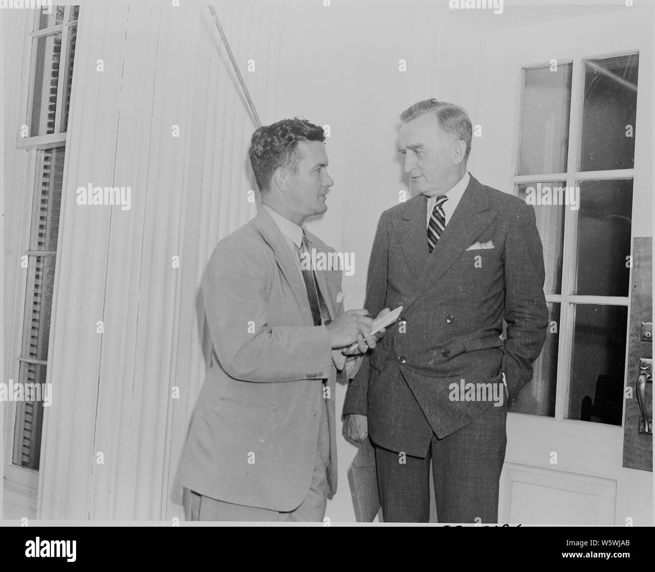 Photograph of a reporter interviewing an unidentified man outside the ...