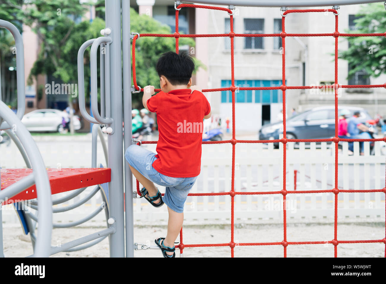 little boy playing on monkey bars at playground Stock Photo - Alamy