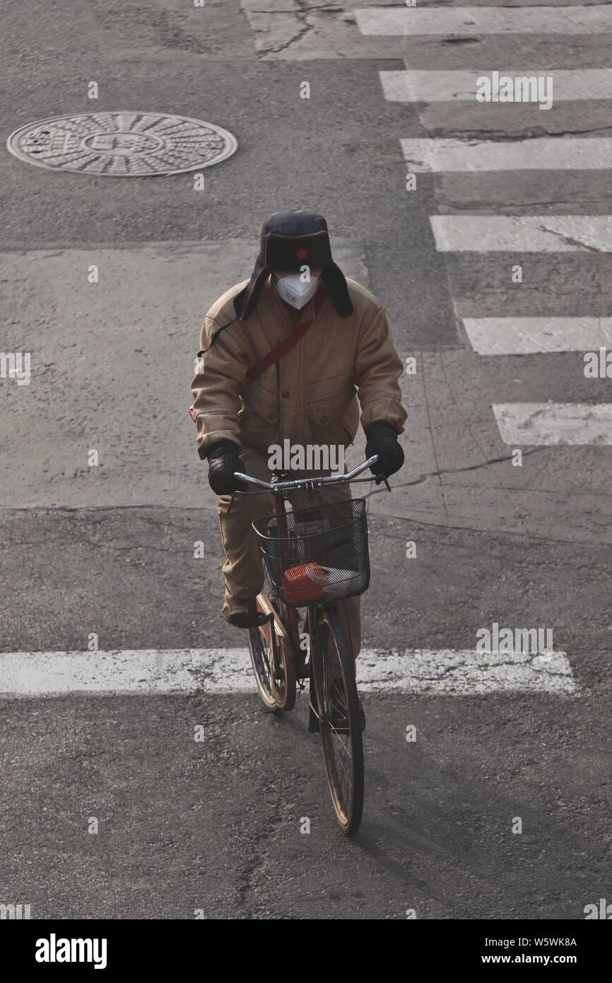 A cyclist wearing face mask against air pollution rides on a road in ...