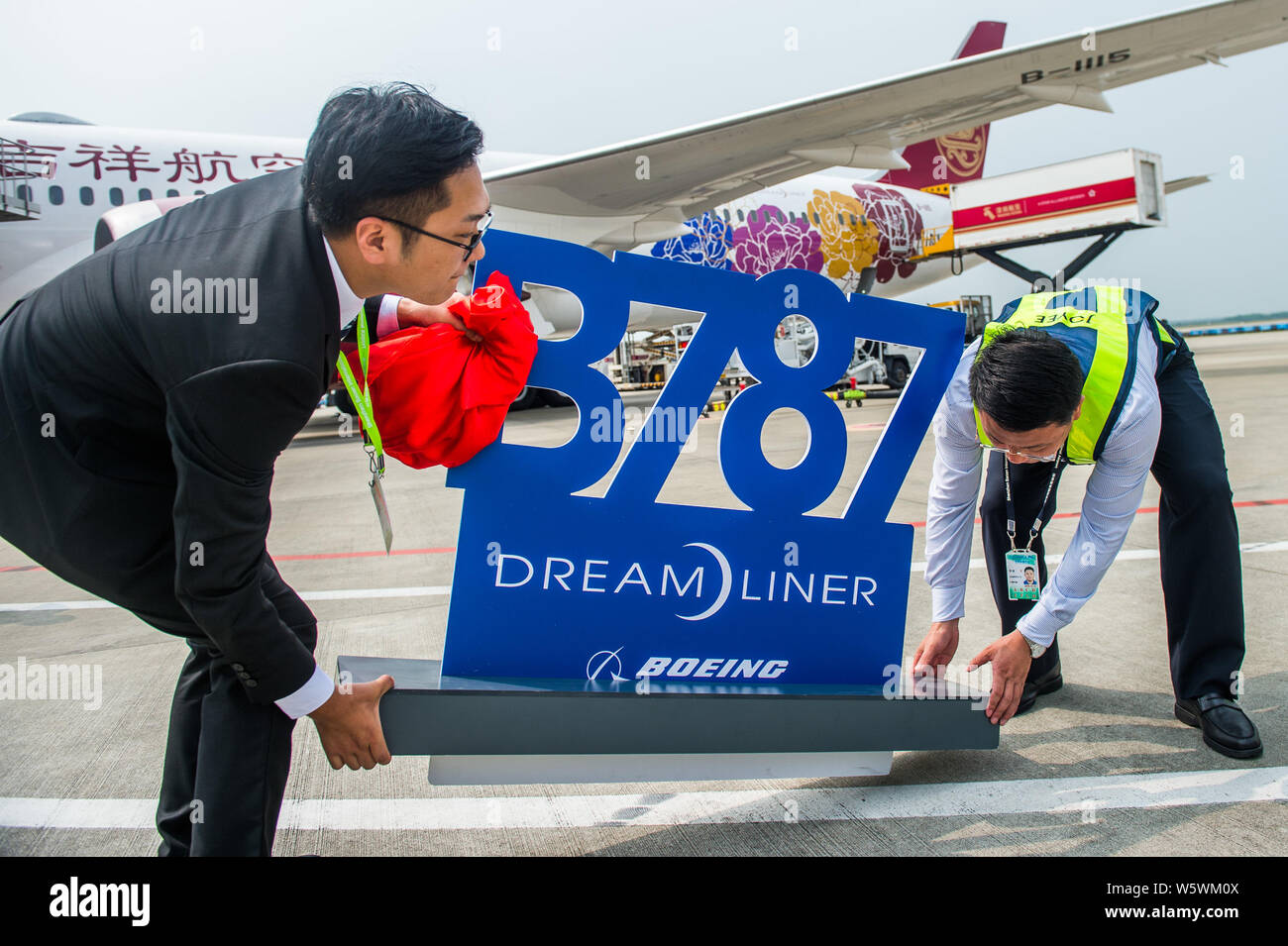 Chinese crew members place a signboard in front of the Boeing 787-9 ...