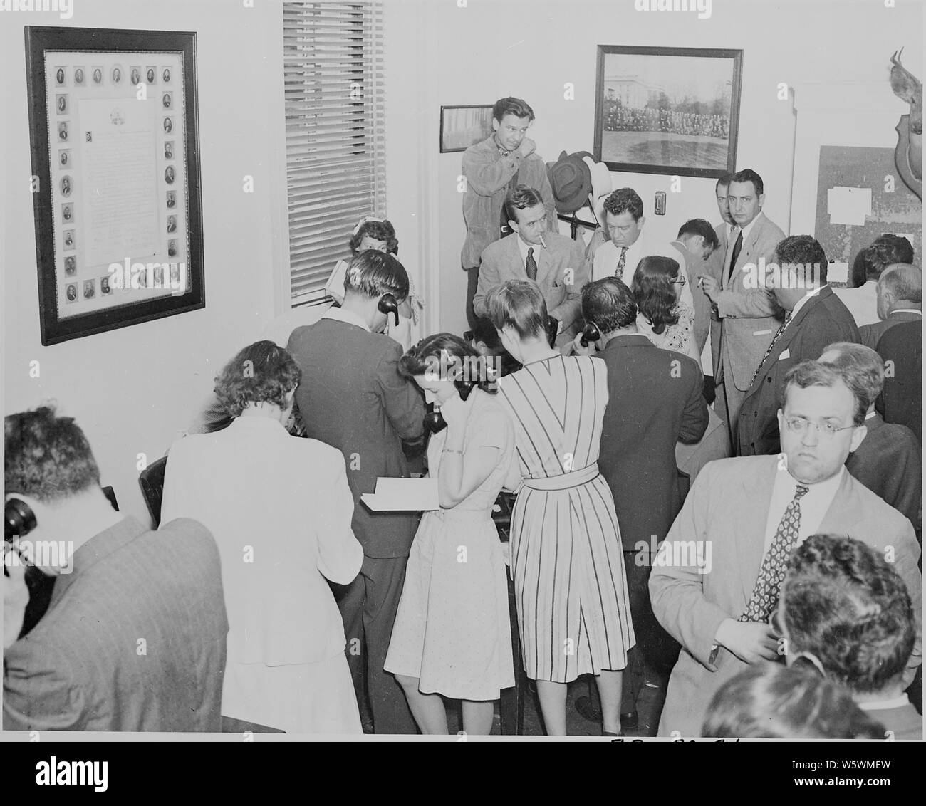 Photograph of reporters on telephones at the White House, transmitting ...