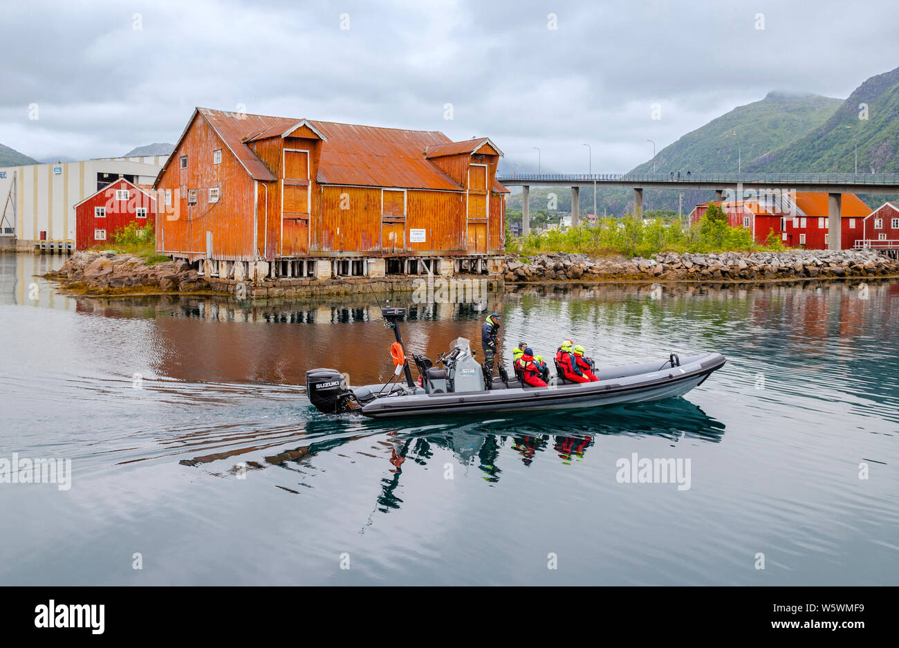 People dressed in thermal suits and safety vests, seated on a RIB boat ...