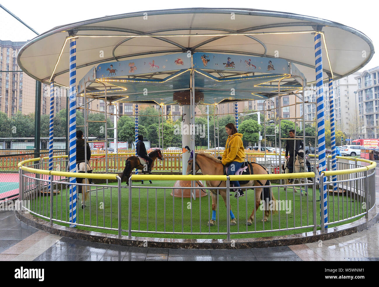 Horses tied to poles walk on the carousel or merry-go-round in circles ...