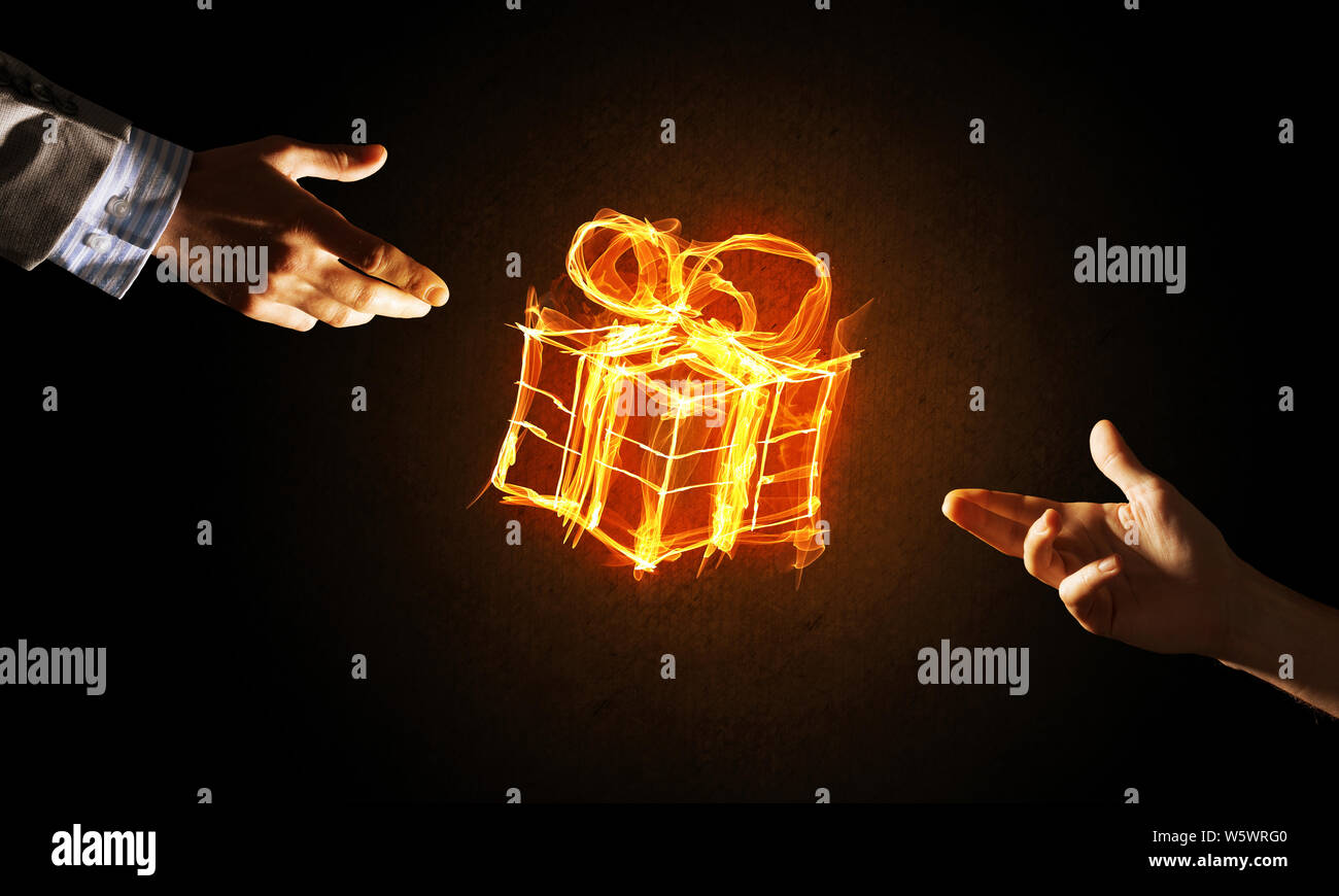 Glowing fire gift box icon in palm on dark background Stock Photo - Alamy