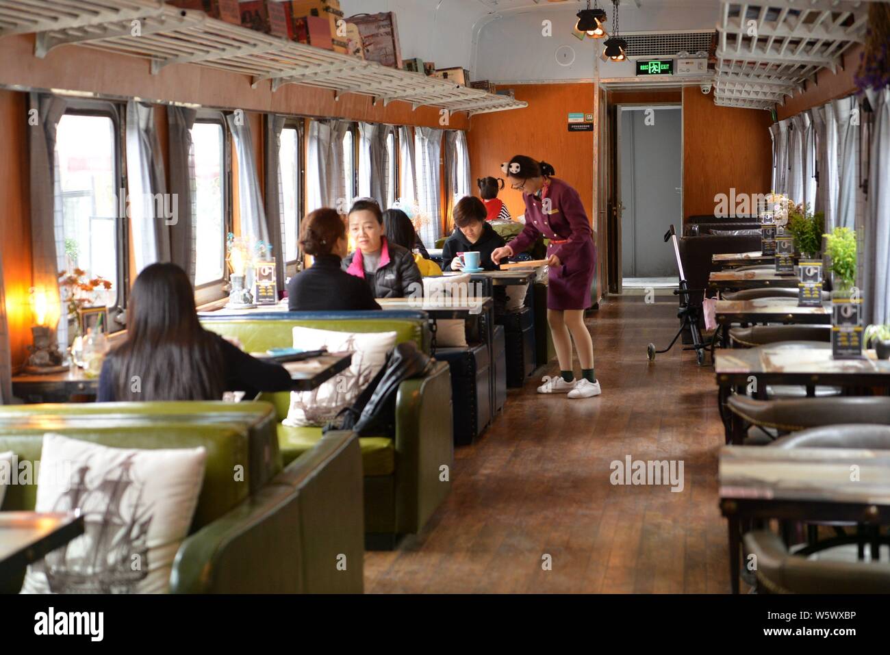 A waitress dressed as a train attendant serves customers at a ...