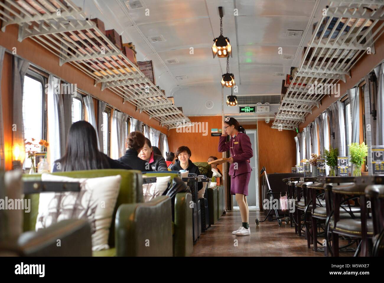 A waitress dressed as a train attendant serves customers at a ...