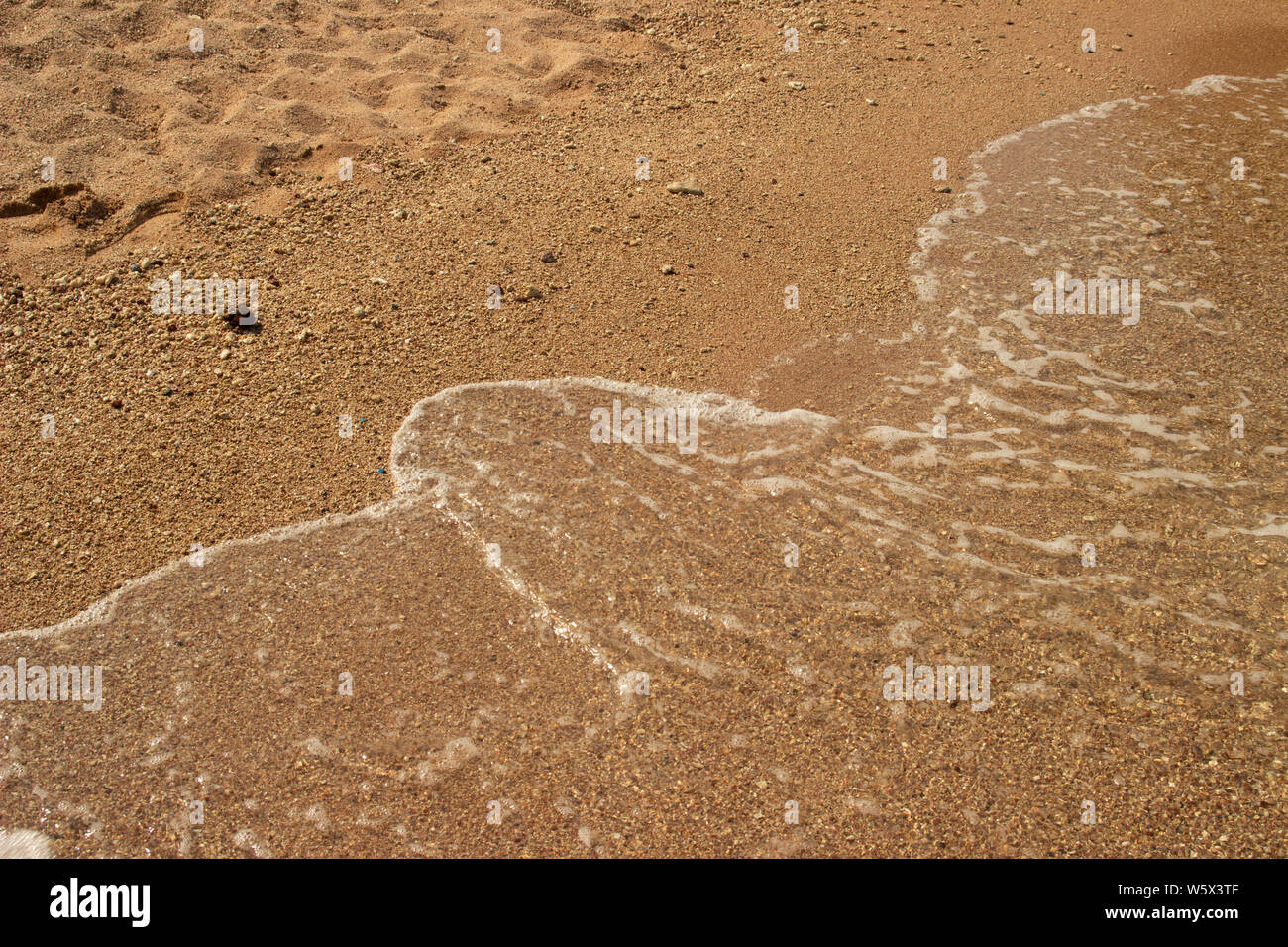 Summer background of hot sand with sea or ocean wave bubbles with copy ...