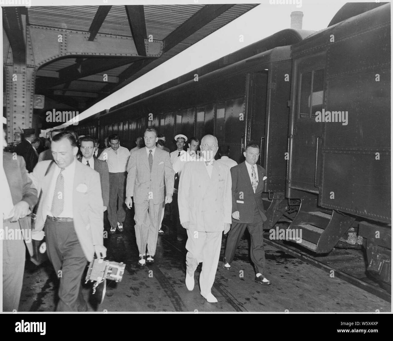 President Harry S. Truman walking in a station, beside the presidential ...